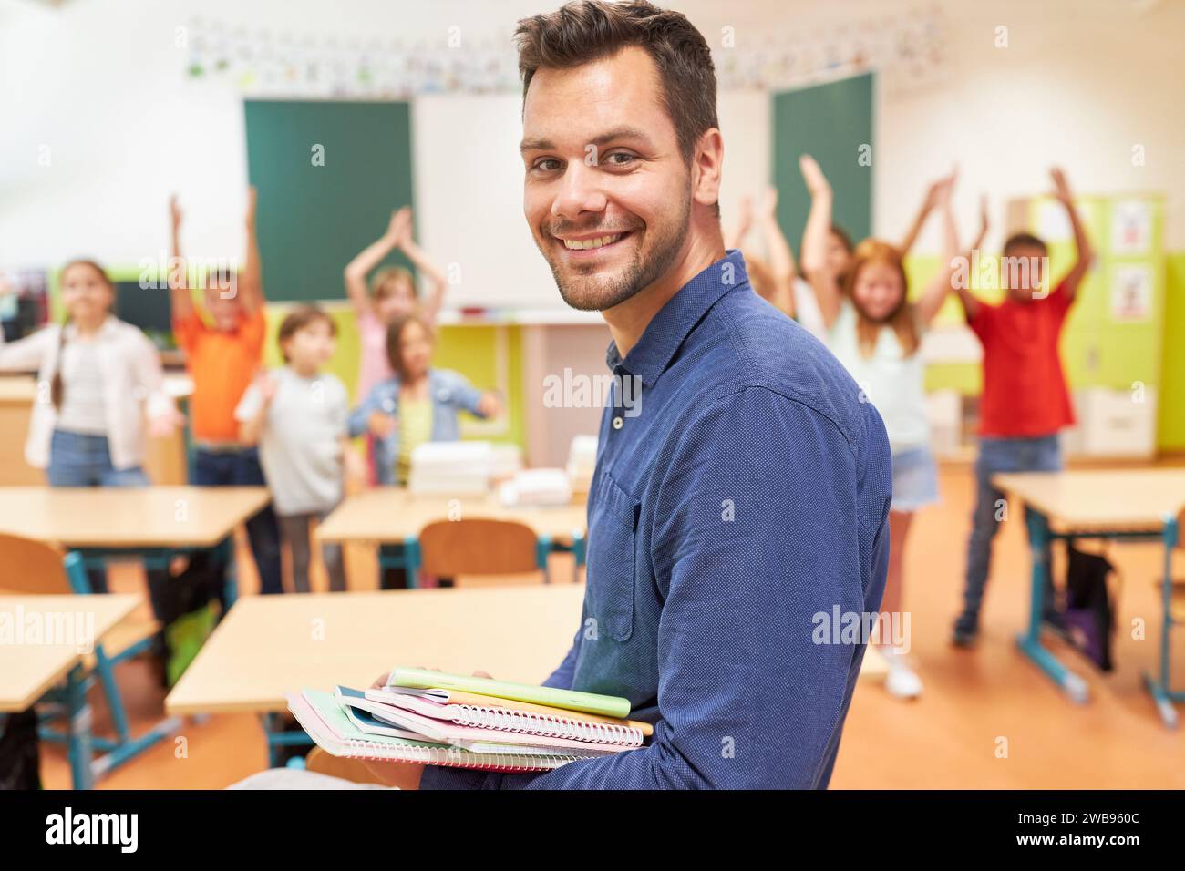 Side view portrait of smiling male teacher holding books while standing ...
