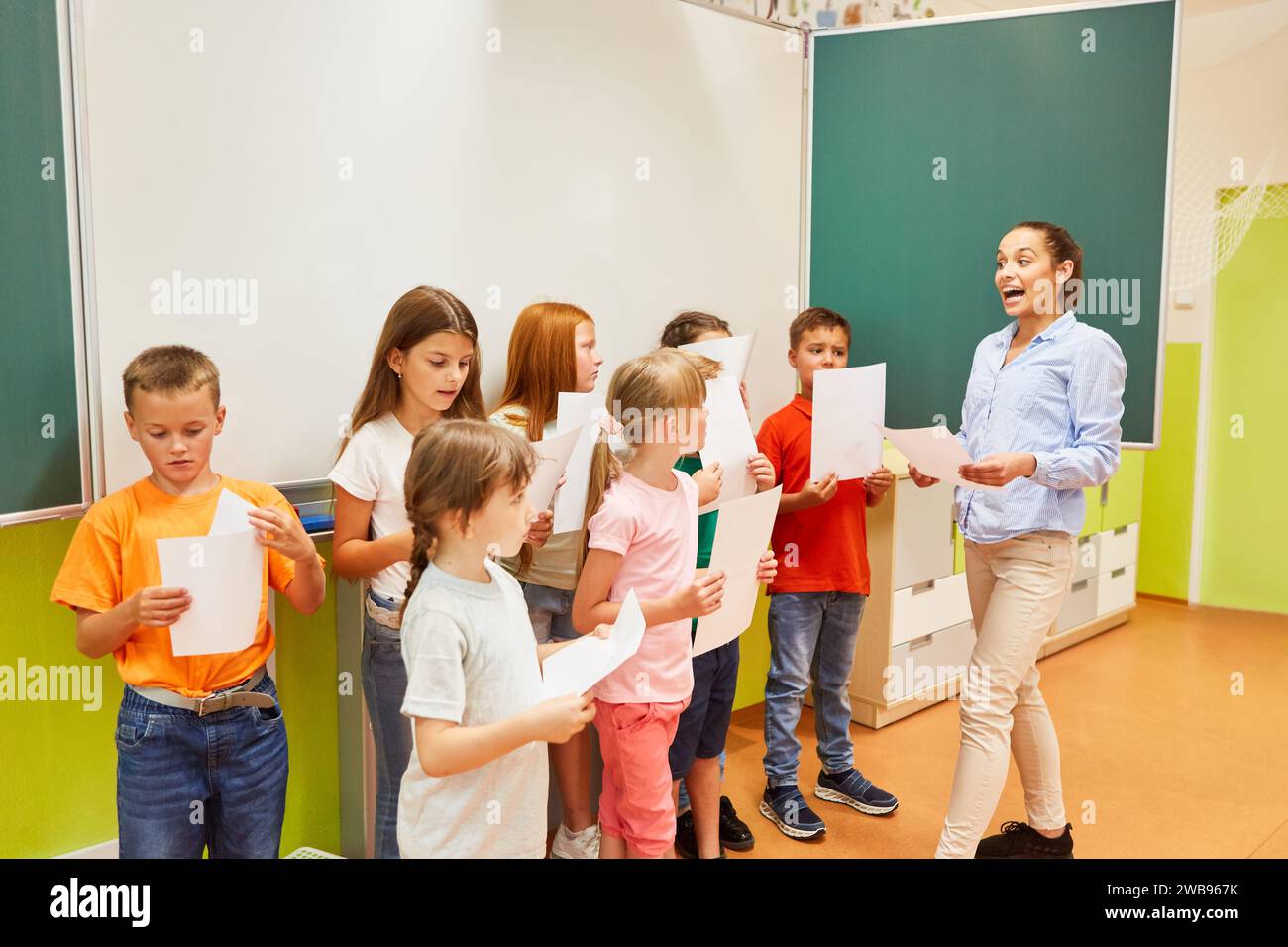 Female teacher distributing sheet to students during choir rehearsal in ...