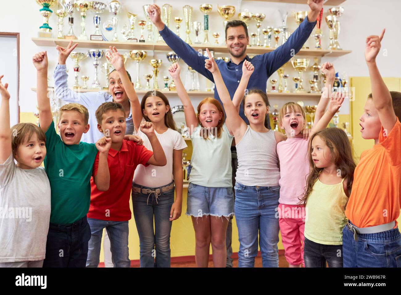 Portrait of male and female teacher cheering with kids while standing ...