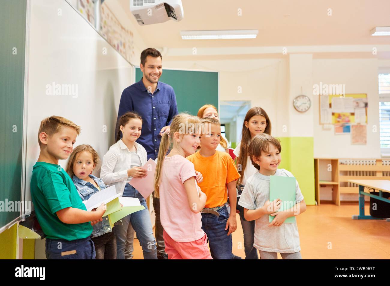 Smiling male teacher standing with group of school students in ...