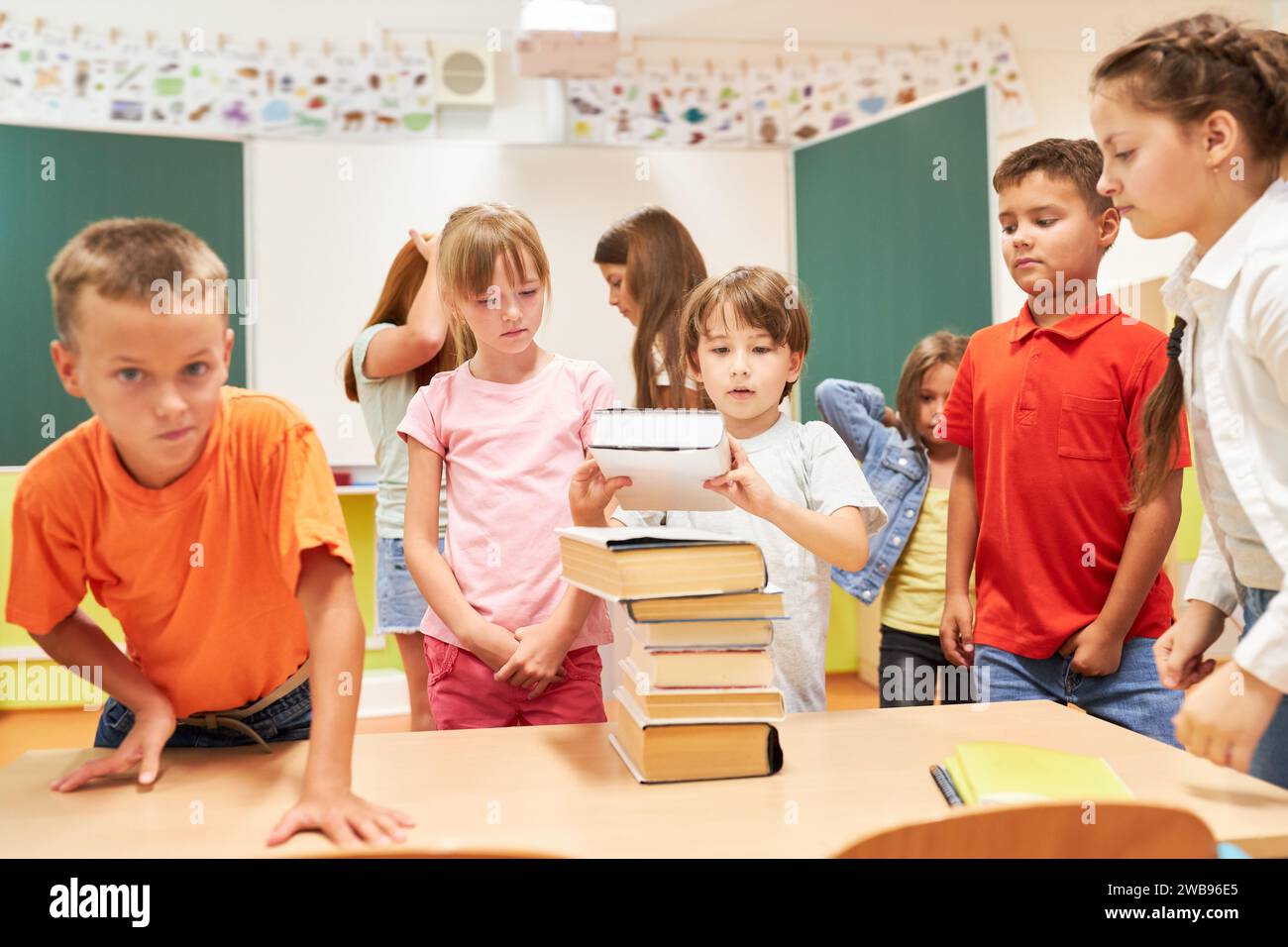 Elementary schoolkids stacking books on bench during activity in ...