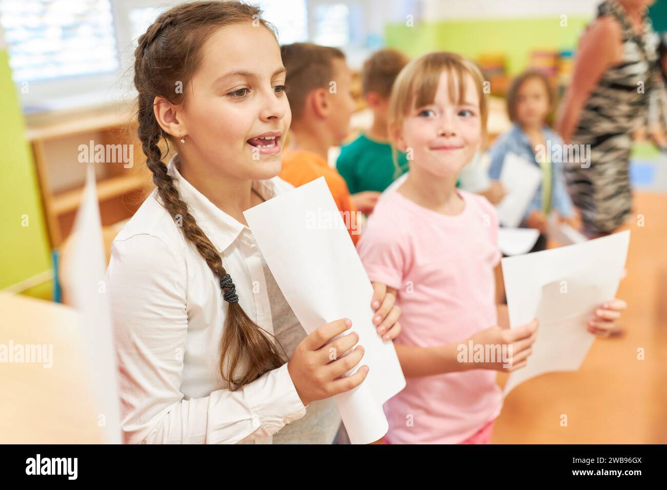 Girl singing during choir rehearsal with friends in classroom at school ...