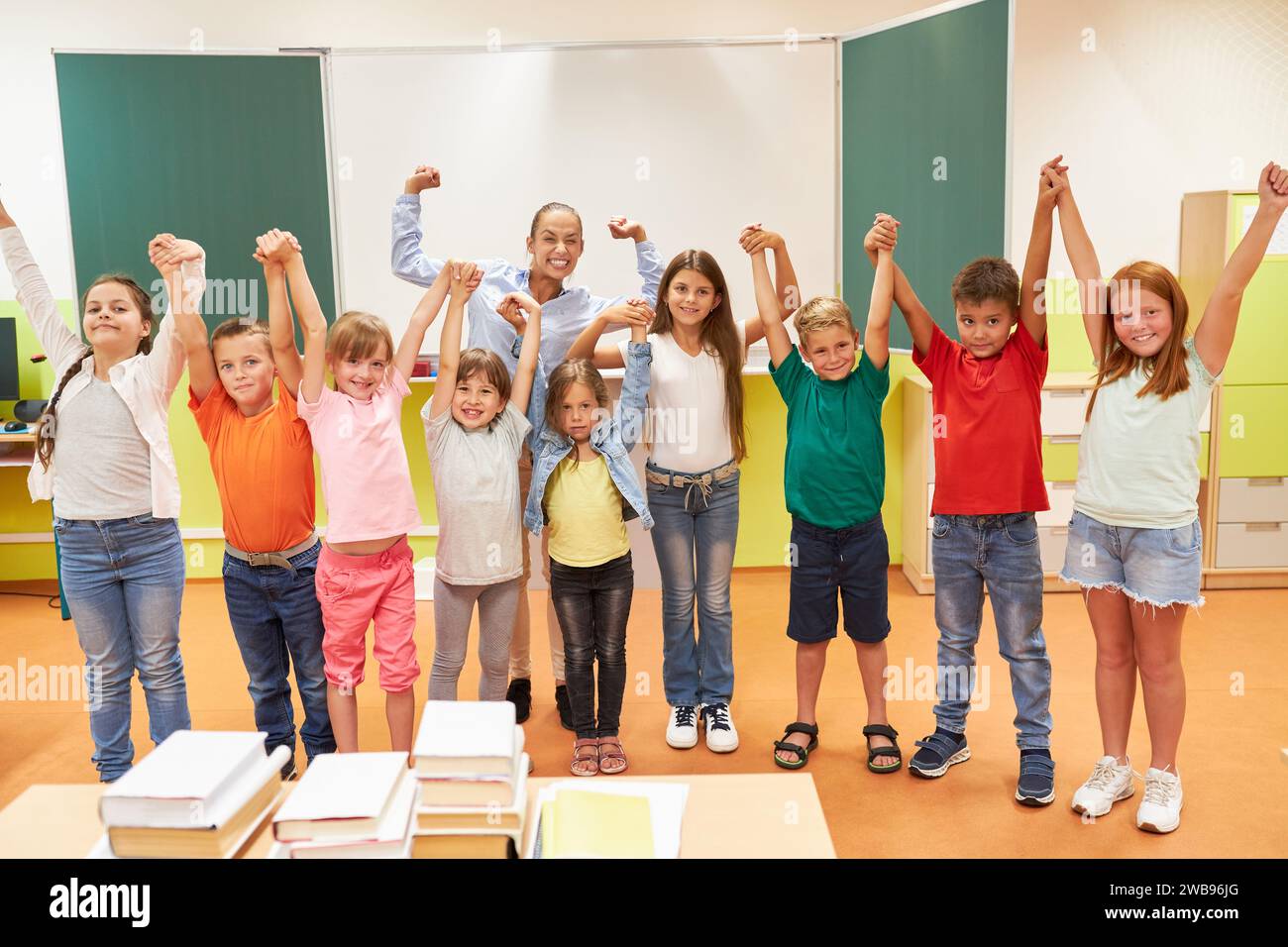 Excited female teacher cheering with diverse students while standing in ...