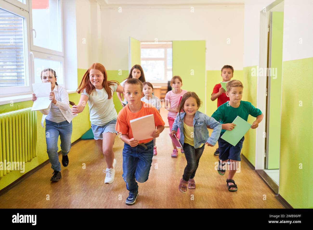Group of excited male and female children running in corridor during ...