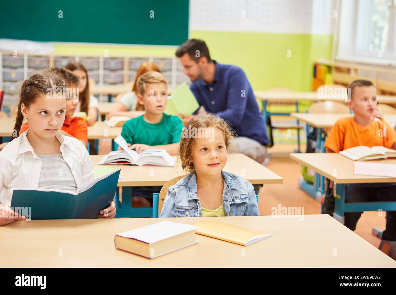 Group of children learning with teacher and books in elementary school ...