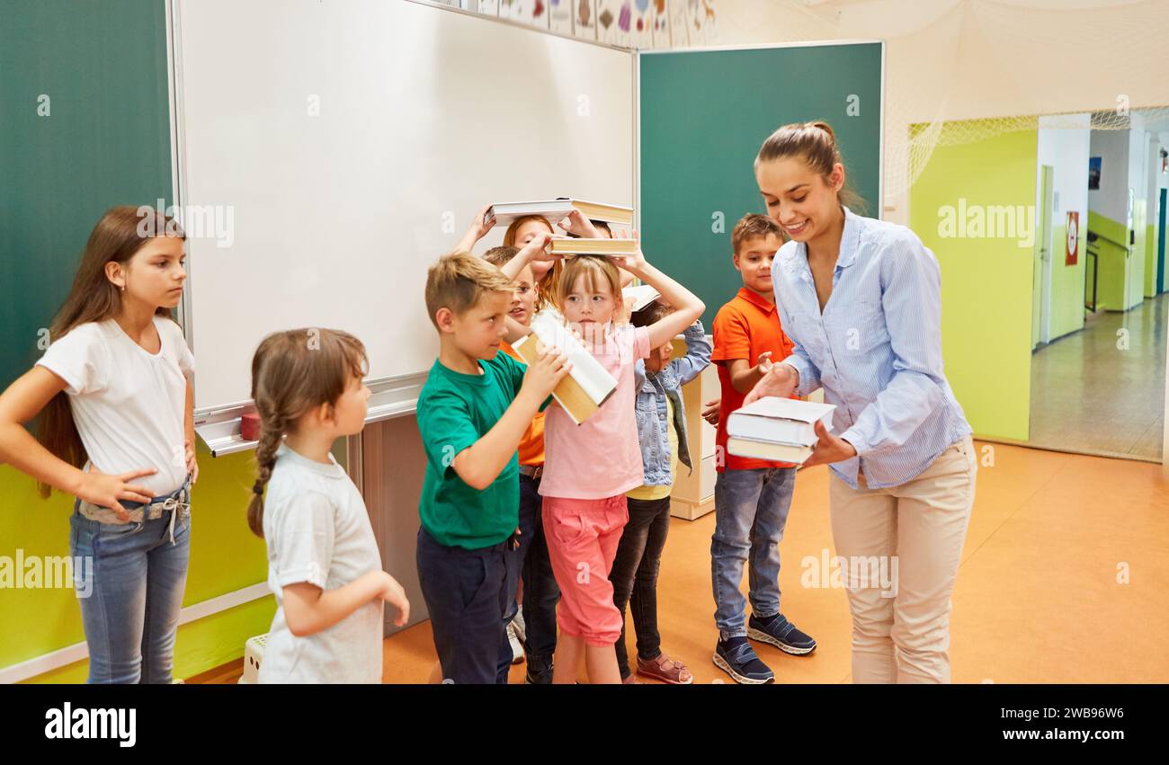 Female teacher distributing books to school students standing in ...