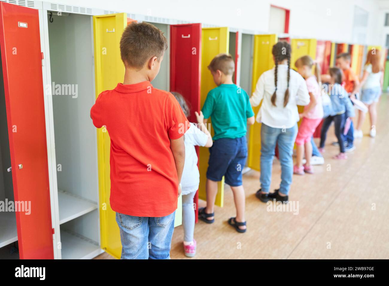 Group of male and female students standing near lockers in hallway at ...