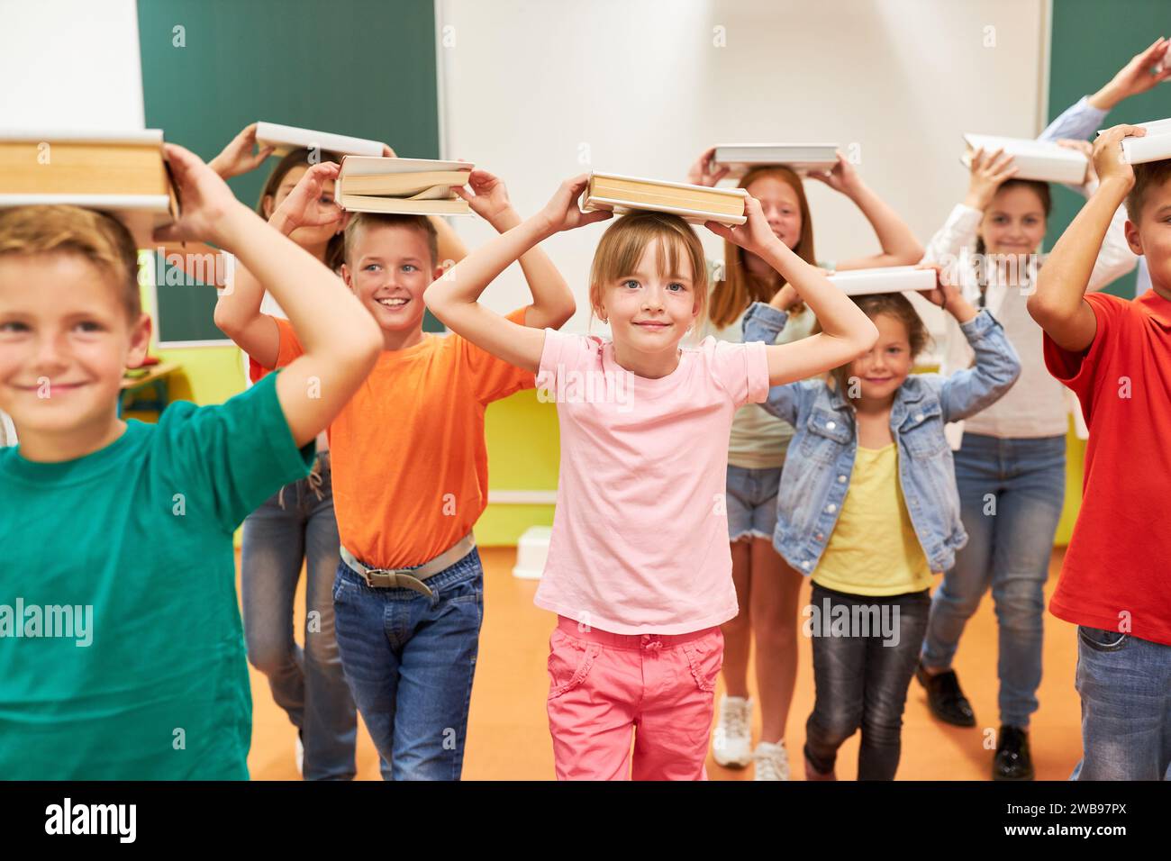 Portrait of elementary school students balancing books on head during ...