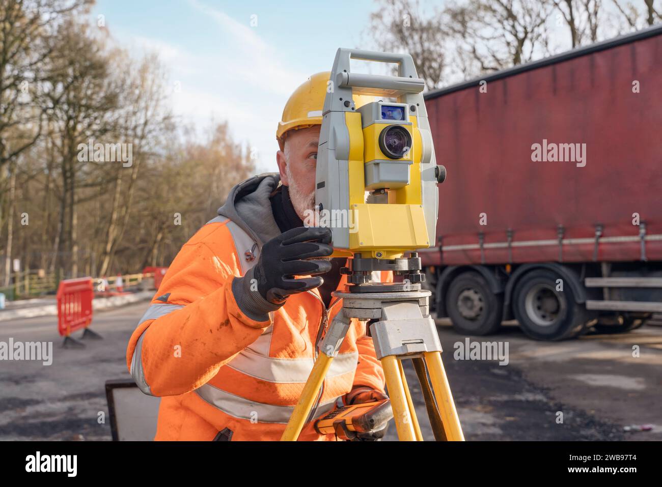 Site engineer operating his instrument during roadworks. Builder using ...