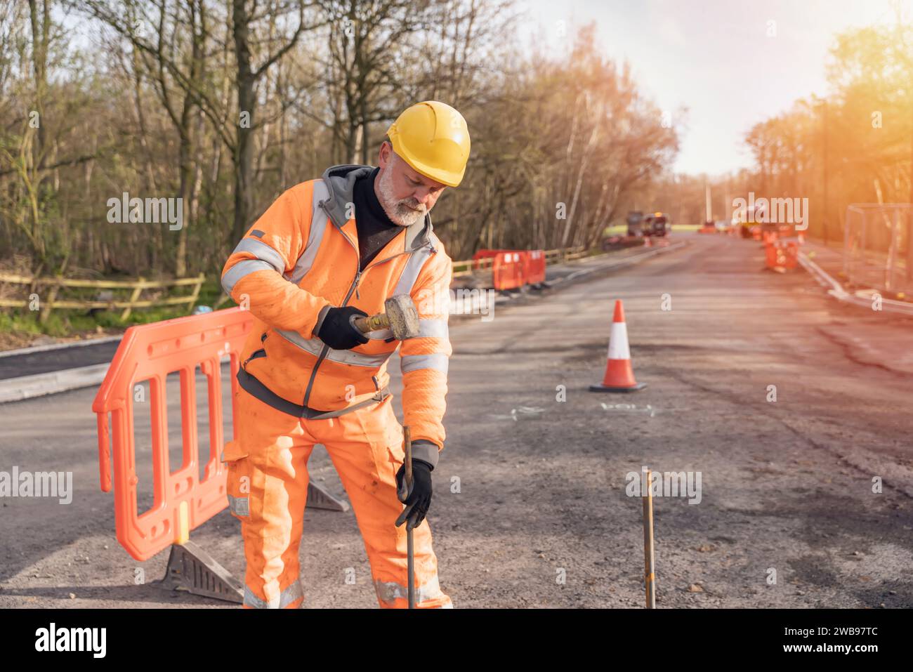 Builder knocking down road setting out steel pins with lump hammer ...