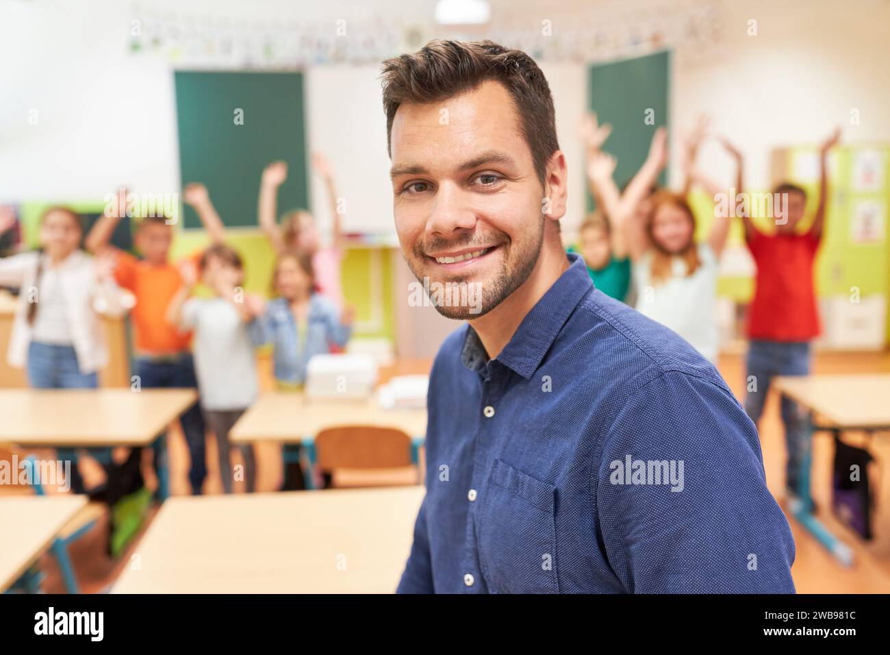 Portrait of smiling male teacher with students in background at school ...