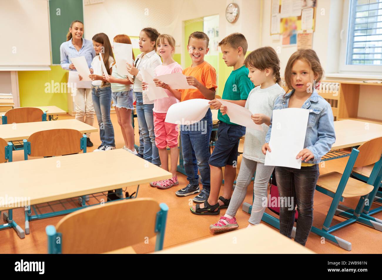 Group of elementary schoolkids doing choir rehearsal while standing ...
