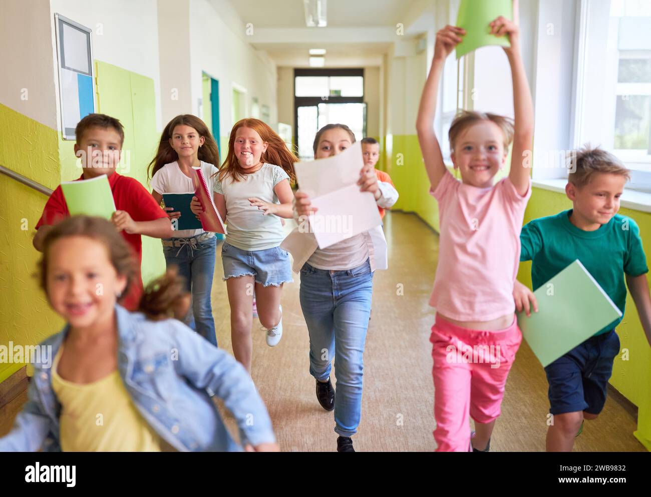 Group of cheerful elementary students running in hallway during recess ...