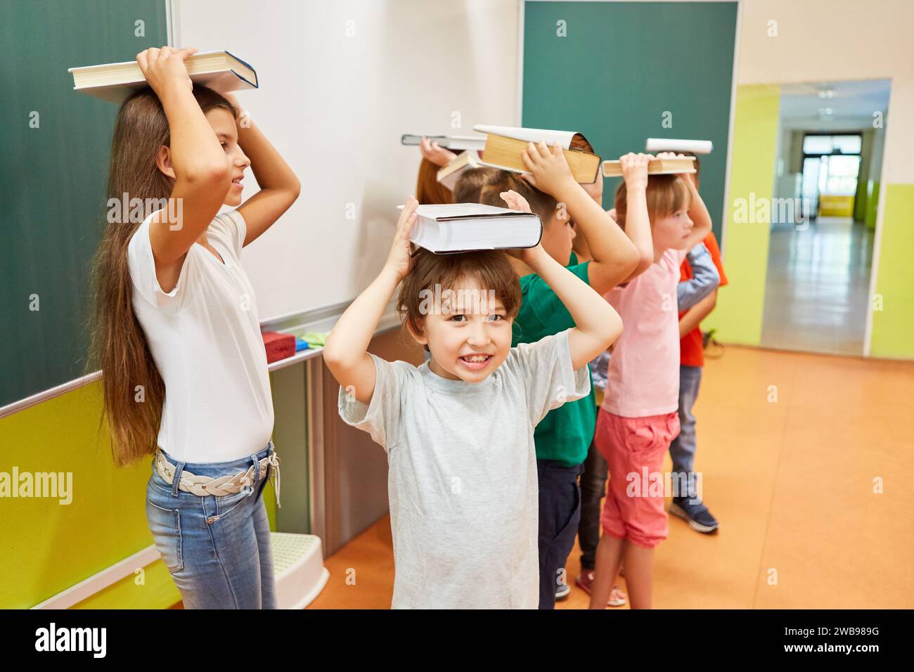 Group of students balancing books overhead while standing together in ...