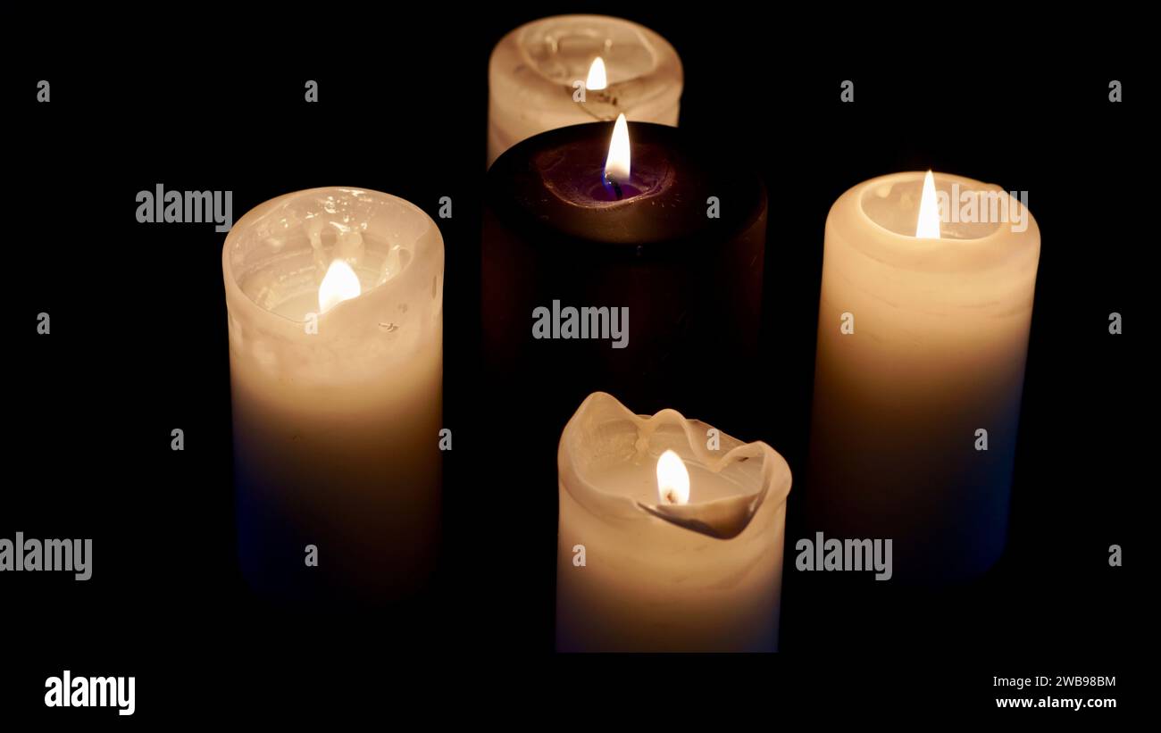 Four white candles surrounding a black candle Stock Photo - Alamy