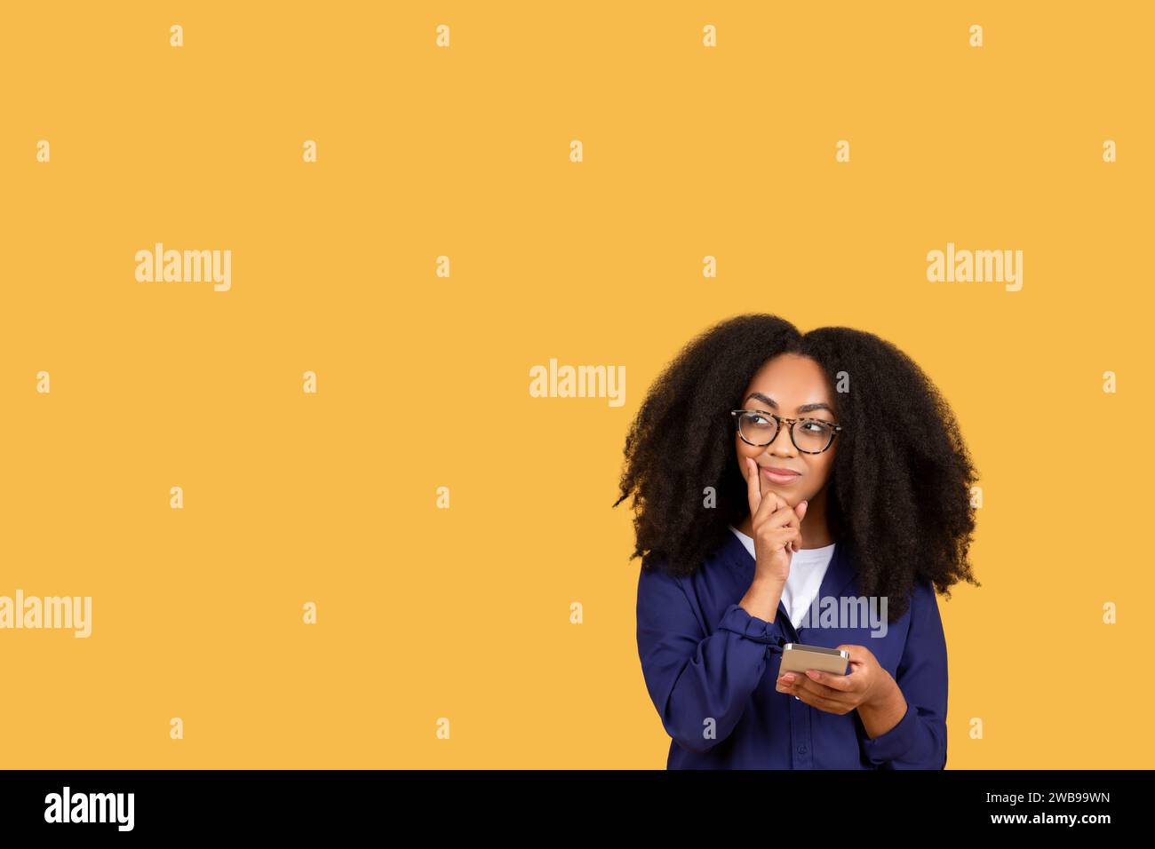 Thoughtful black lady student in glasses holding cellphone, gazing at ...