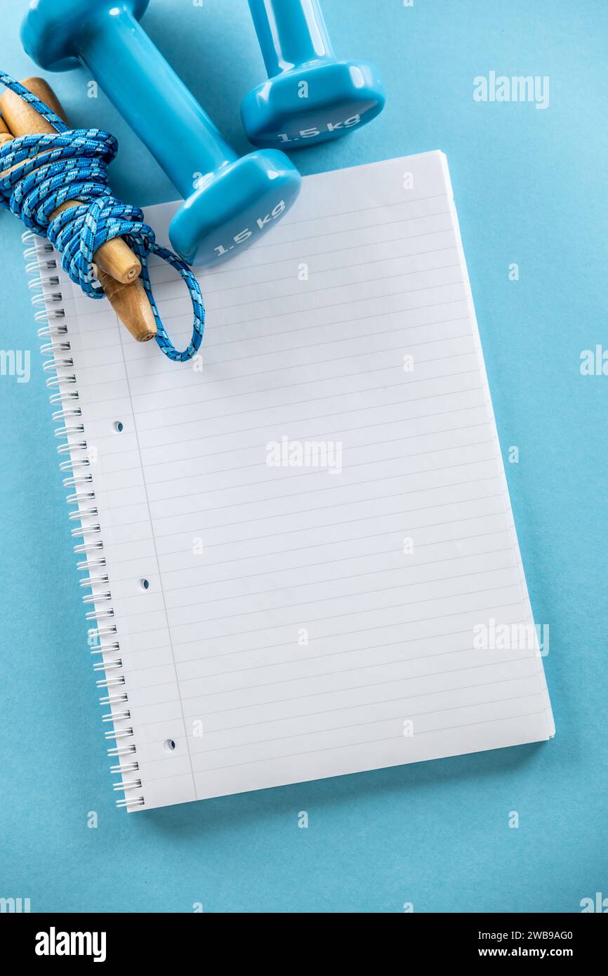 An empty notebook and blue dumbbells and a skipping rope led him. Sport ...