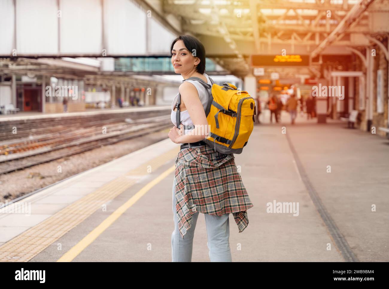 woman with backpack while at the train station and the train is ...