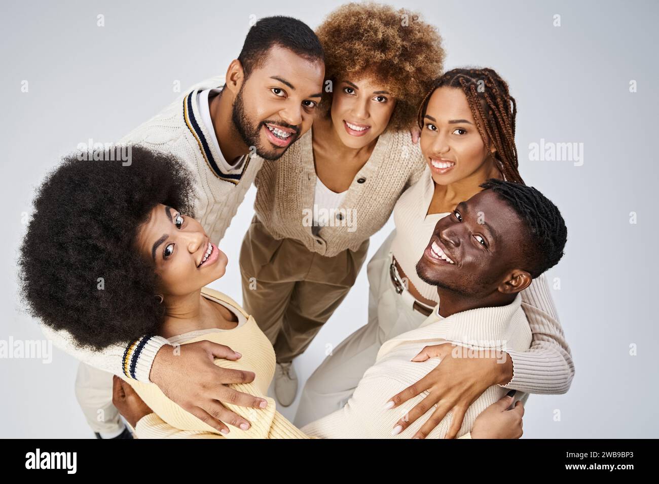 top view of happy african american people bonding and hugging on grey ...