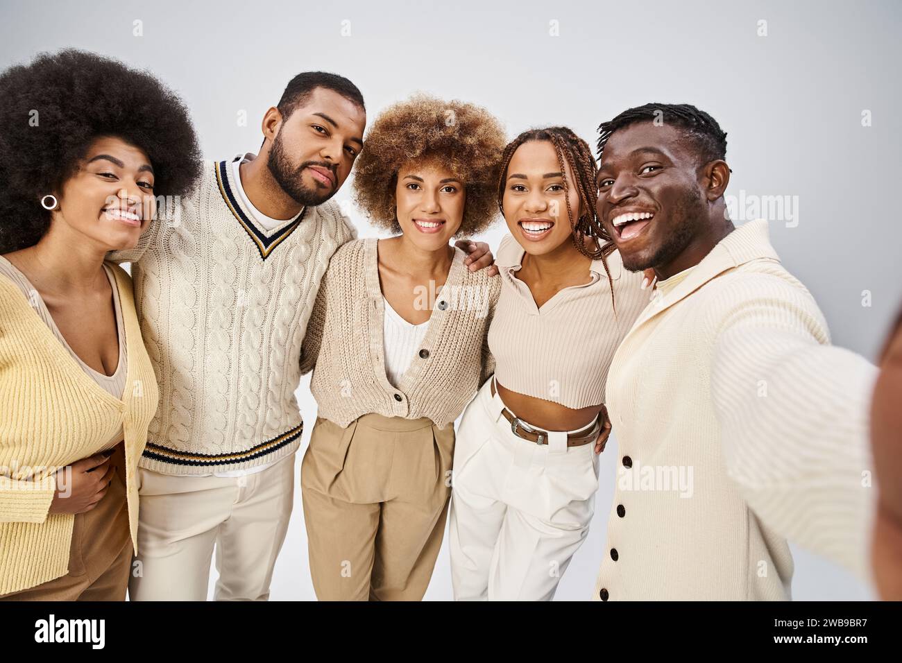 group of positive african american friends bonding and hugging on grey ...