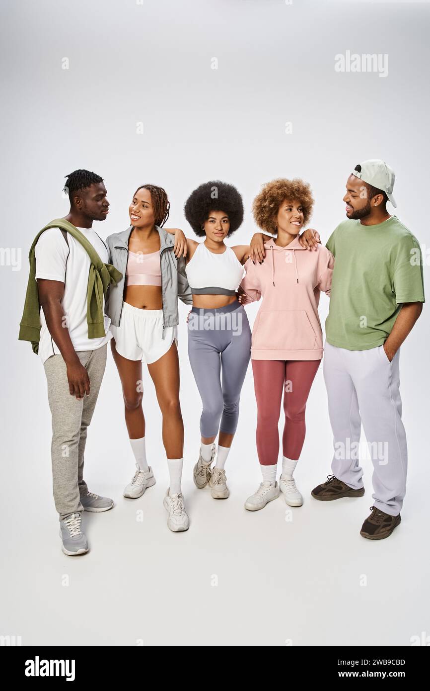 group of happy young african american friends standing together on grey ...