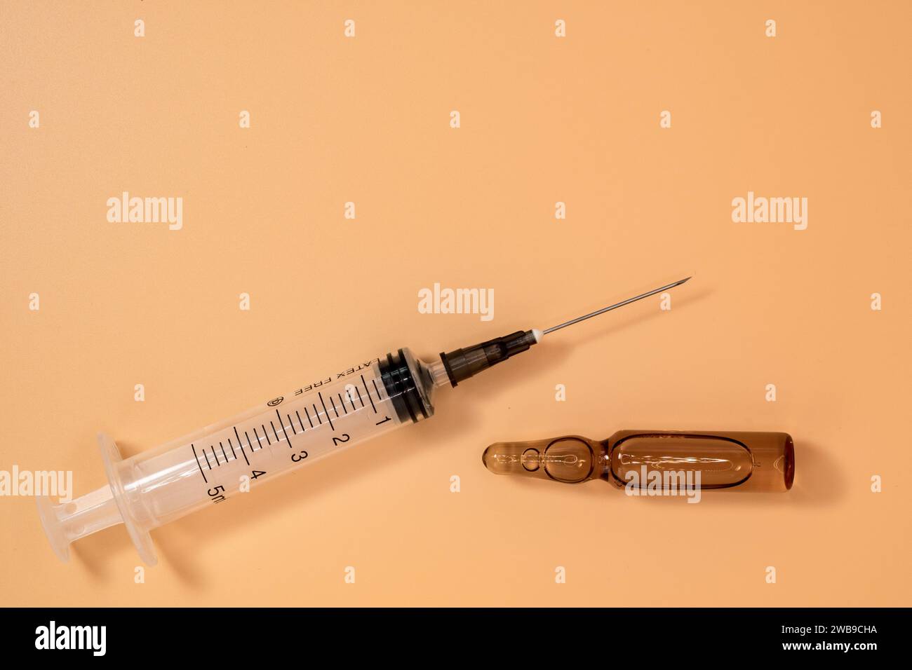 Full 5ml syringe with needle on peach background. Next to it is the ...