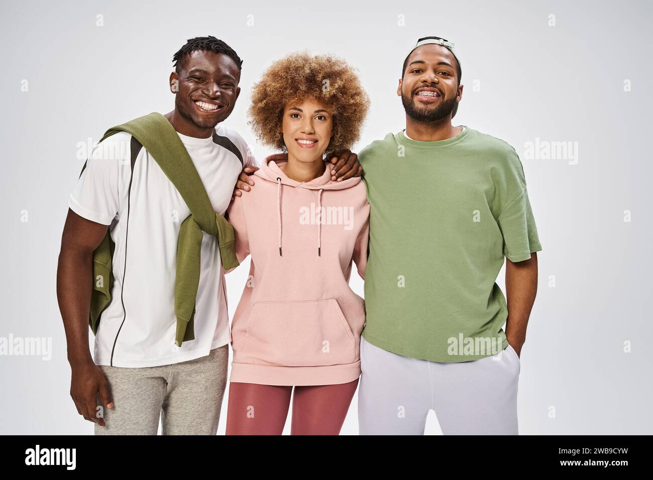 cheerful african american friends standing and hugging on grey ...