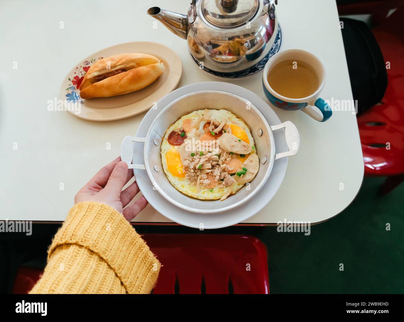 Fried eggs in a small pan with pork and sausages serving on table with ...