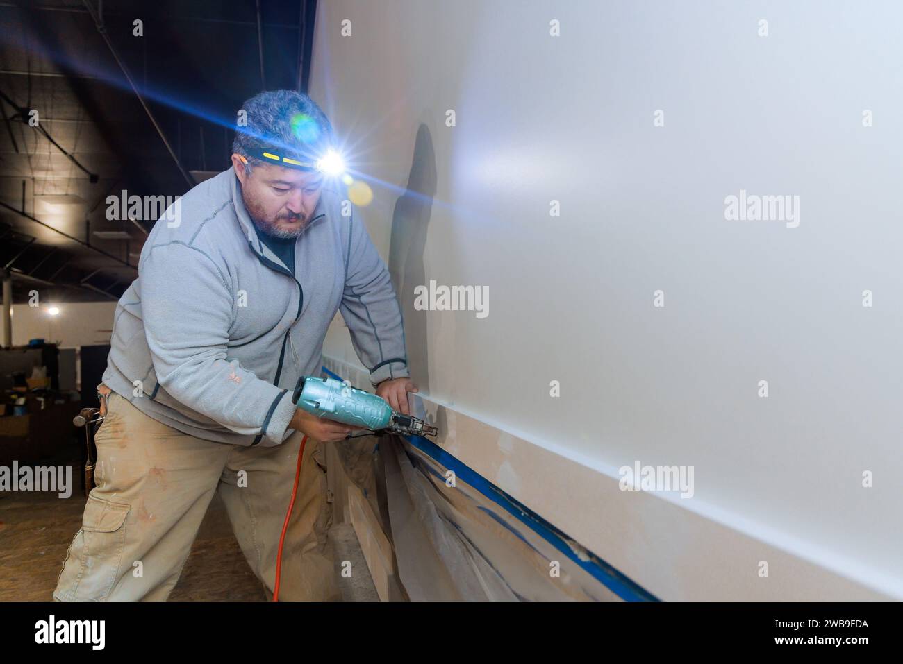 Contractor nails wooden trim moldings during installation to new home ...