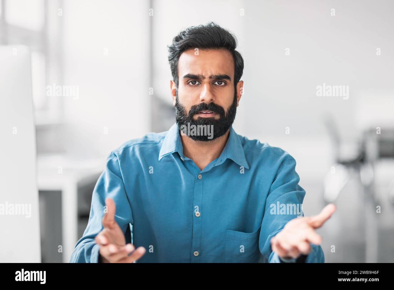 Skeptical indian businessman with questioning gesture, office interior ...