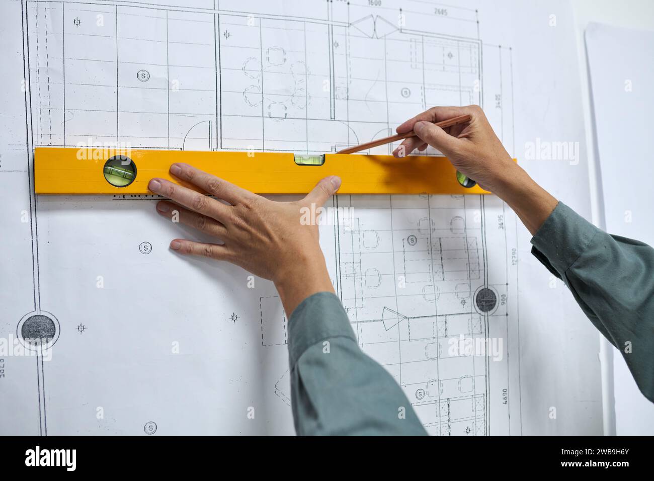 Hands of builder using construction level when measuring line on ...