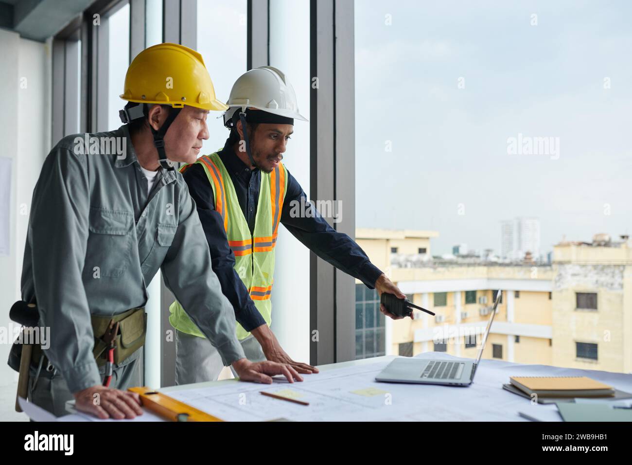 Construction workers looking at chart on laptop screen when discussing ...