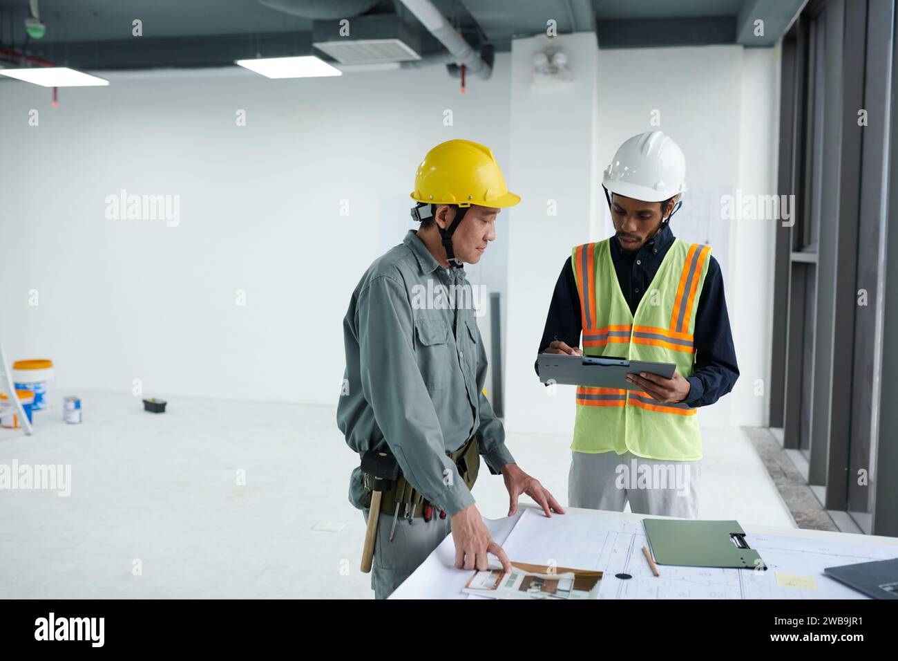 Construction worker talking to builder about details of blueprint Stock ...