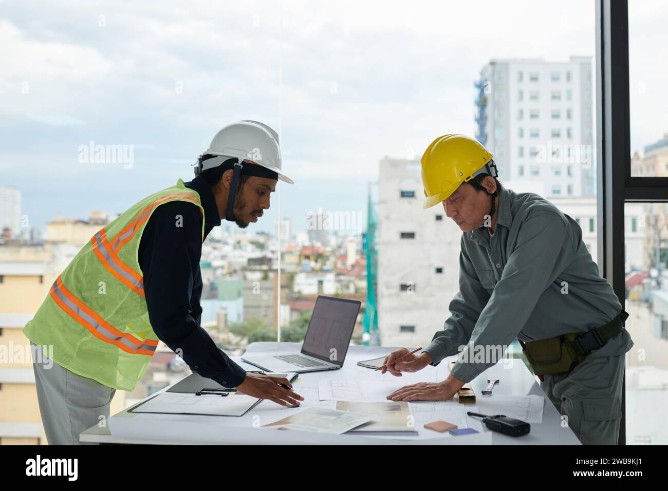 Engineer and construction worker bending over table with blueprints Stock Photo - Alamy