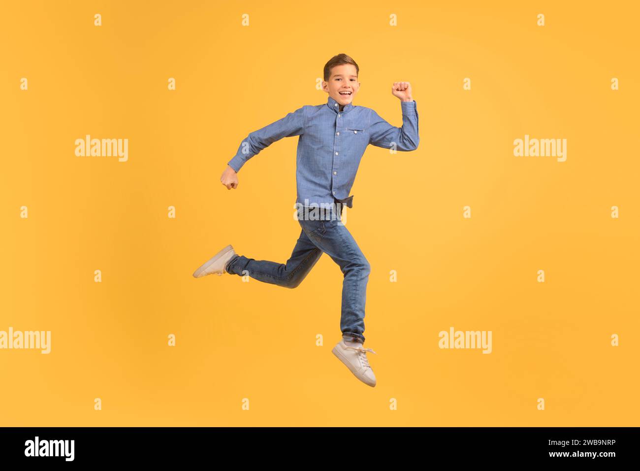 Dynamic teen boy jumping in air against yellow studio background Stock ...