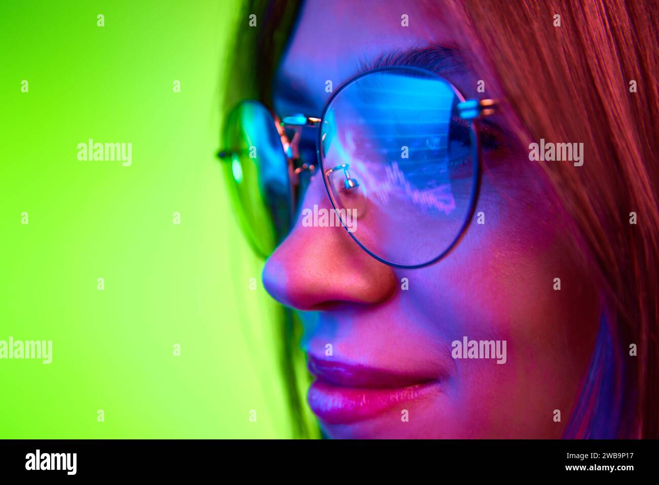 Focused developer, woman wears glasses working on computer looking at programming code which ...