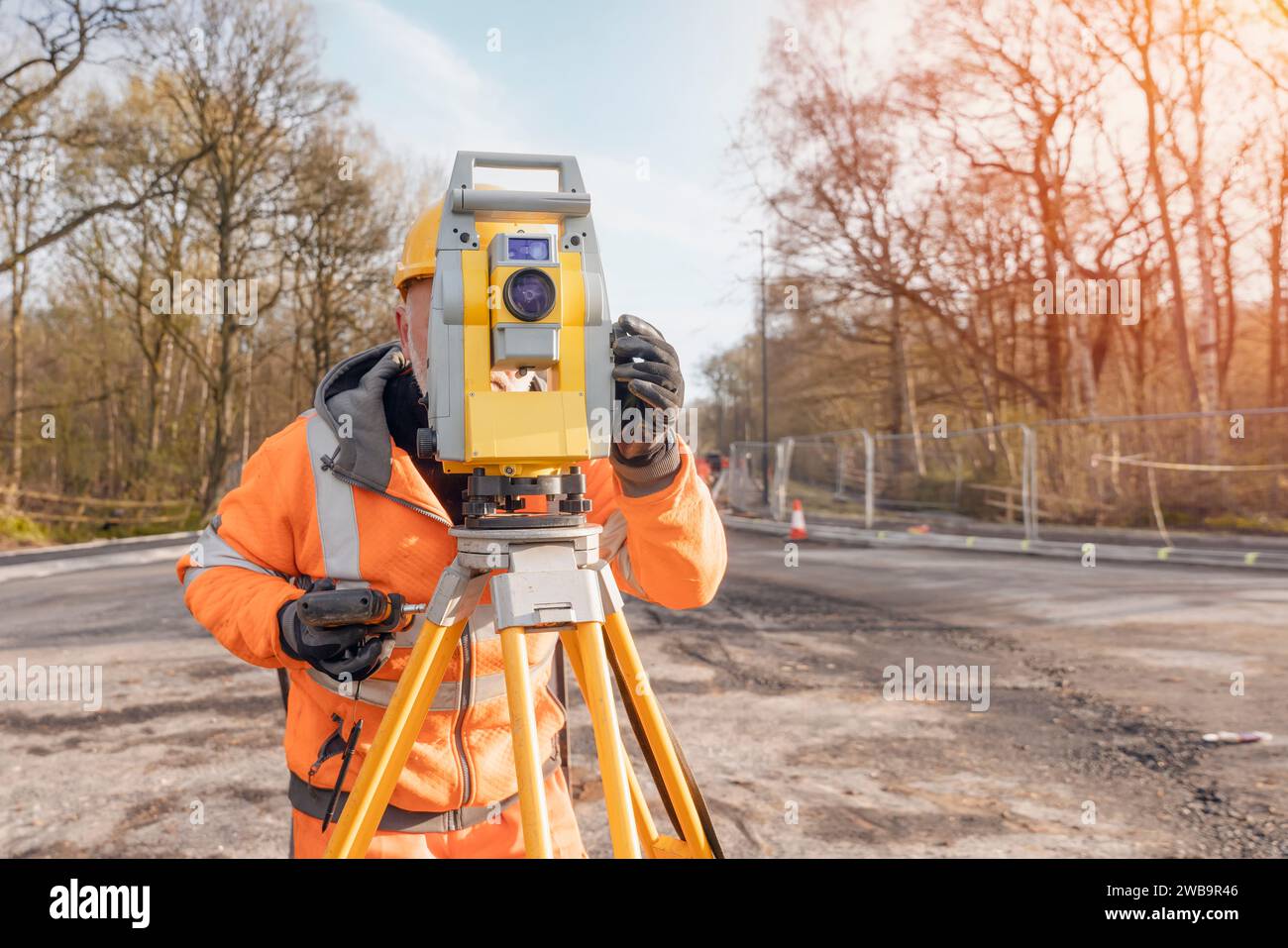 Site engineer operating his instrument during roadworks. Builder using ...