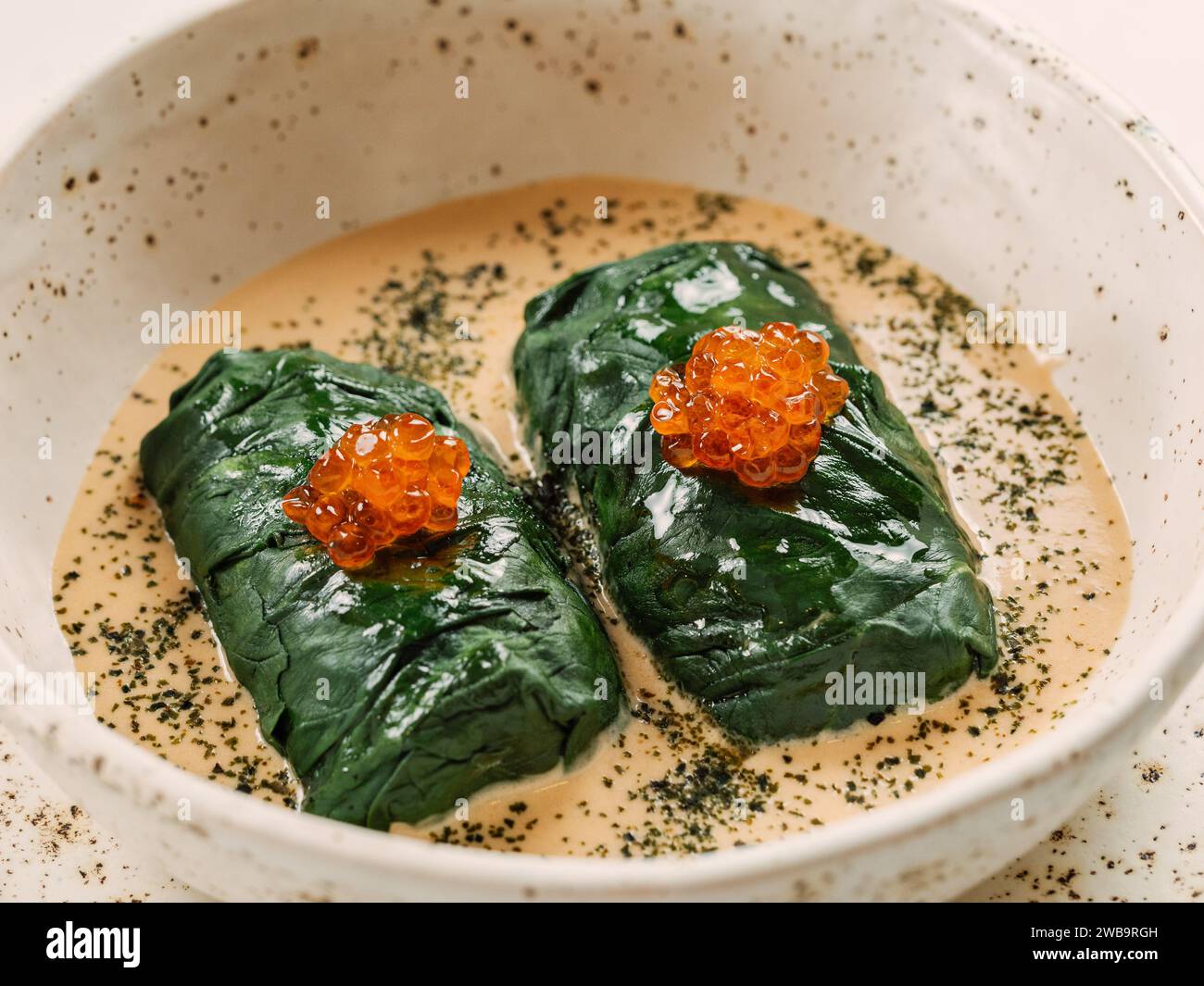 Stuffed green cabbage rolls with sauce in restaurant-style plating ...