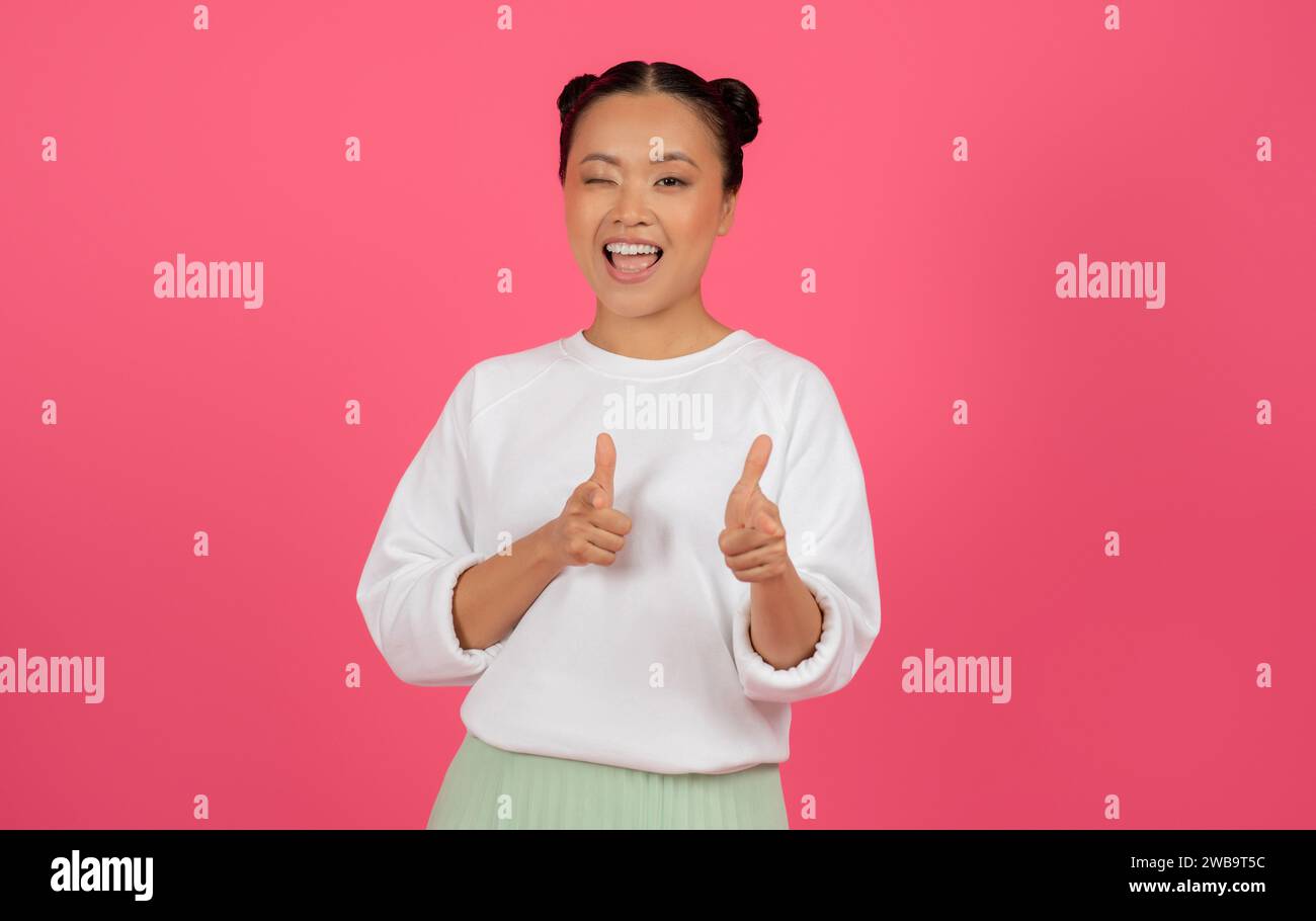 Gotcha. Laughing asian lady winking and pointing index finger at camera ...