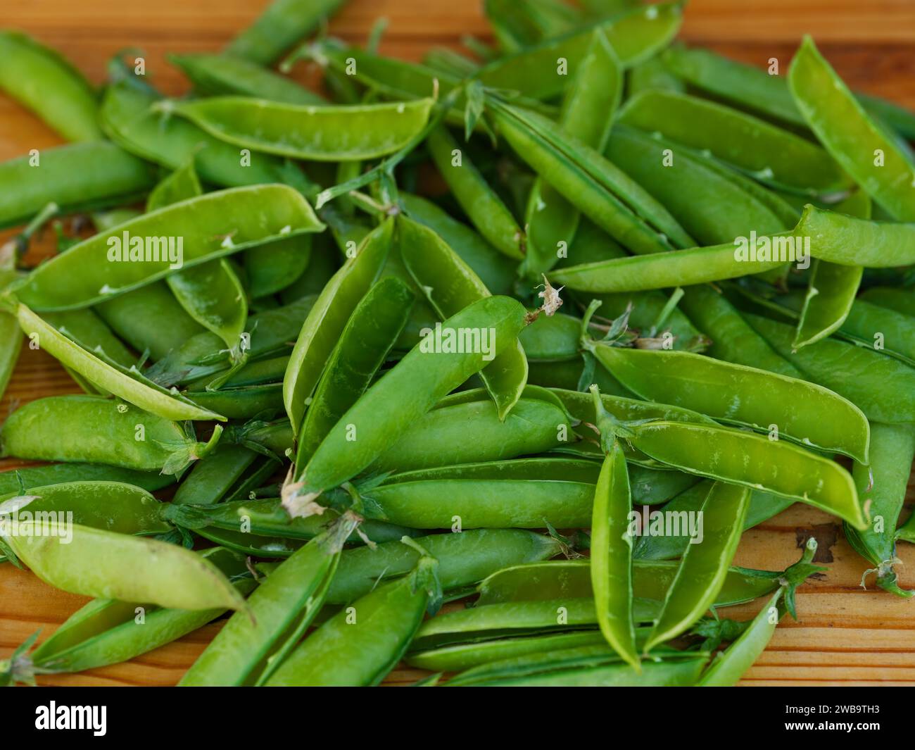 A heap of empty open green pea pods on wooden background Stock Photo ...