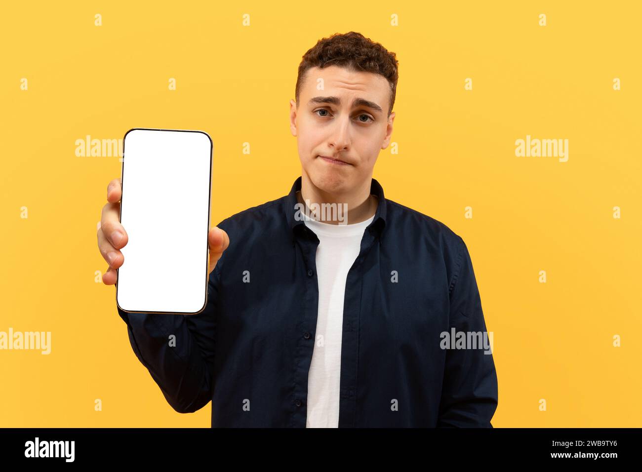 Confused young man showing cell phone with blank screen Stock Photo - Alamy