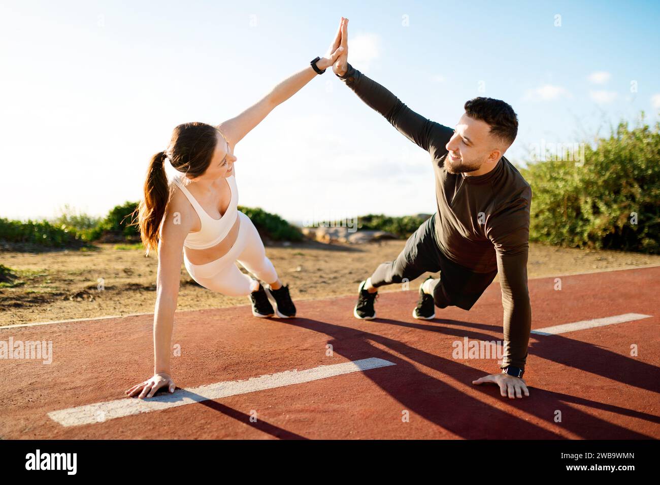Couple giving high-five during side plank workout Stock Photo - Alamy