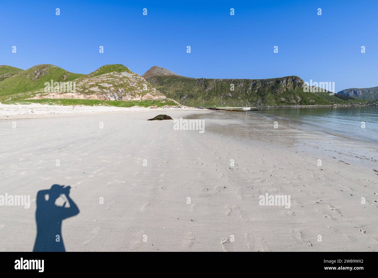 Photographer's shadow cast on Haukland Beach's sandy shore, with a ...