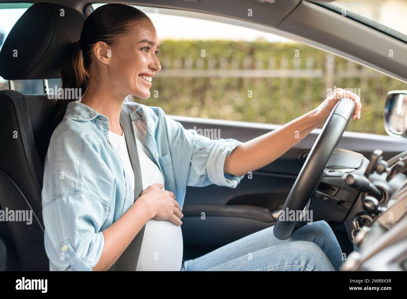 Pregnant lady driving modern car sitting with hand on belly Stock Photo ...
