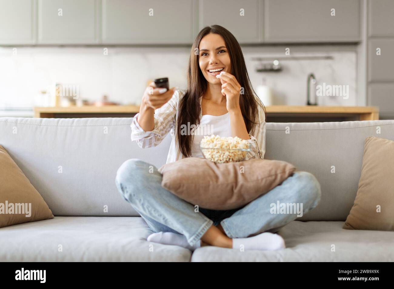 Happy Young Woman Holding Remote Controller And Eating Popcorn At Home ...