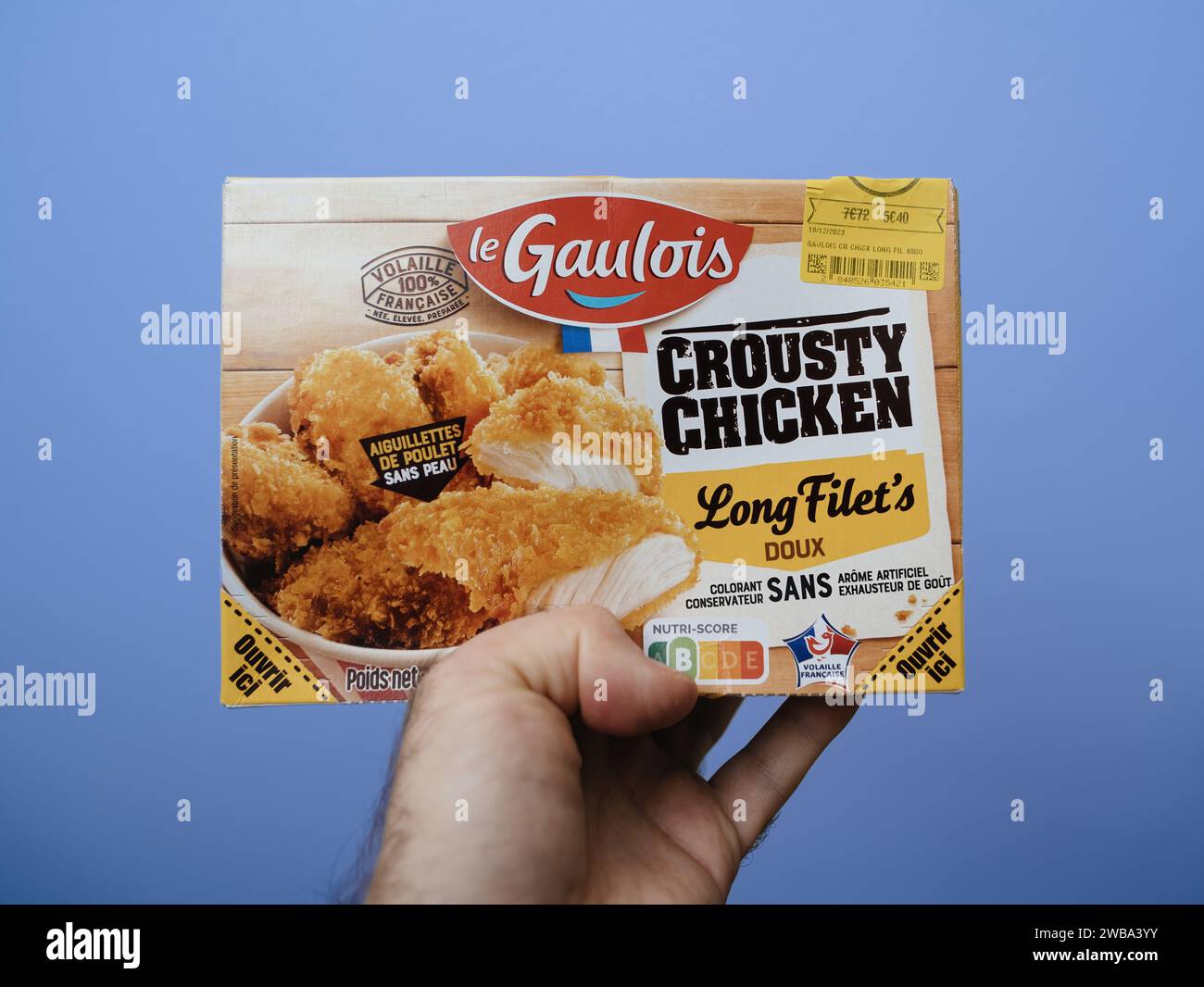 Paris, France - Dec 20, 2023: A man's hand presenting a package of Le Gaulois Crousty chicken ...