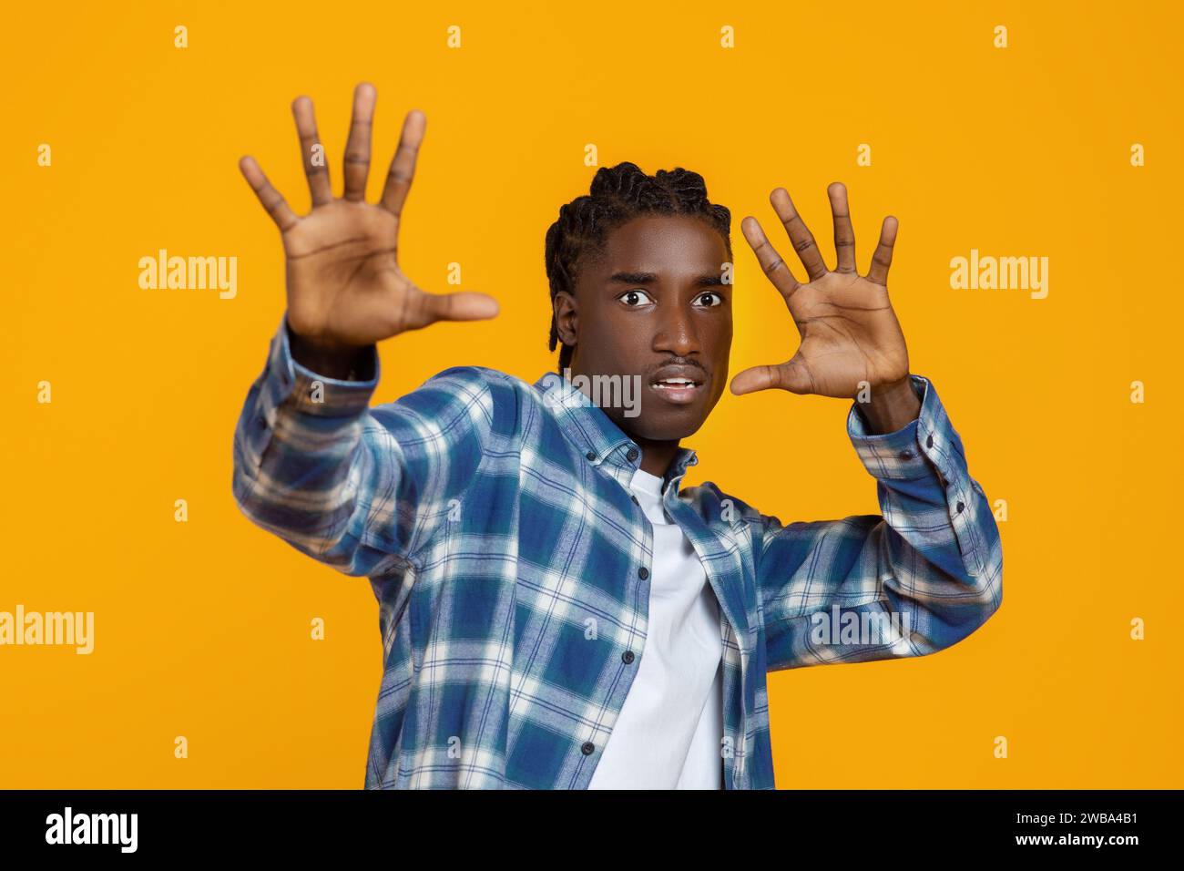 Scared young black man in plaid shirt raising hands and saying stop ...