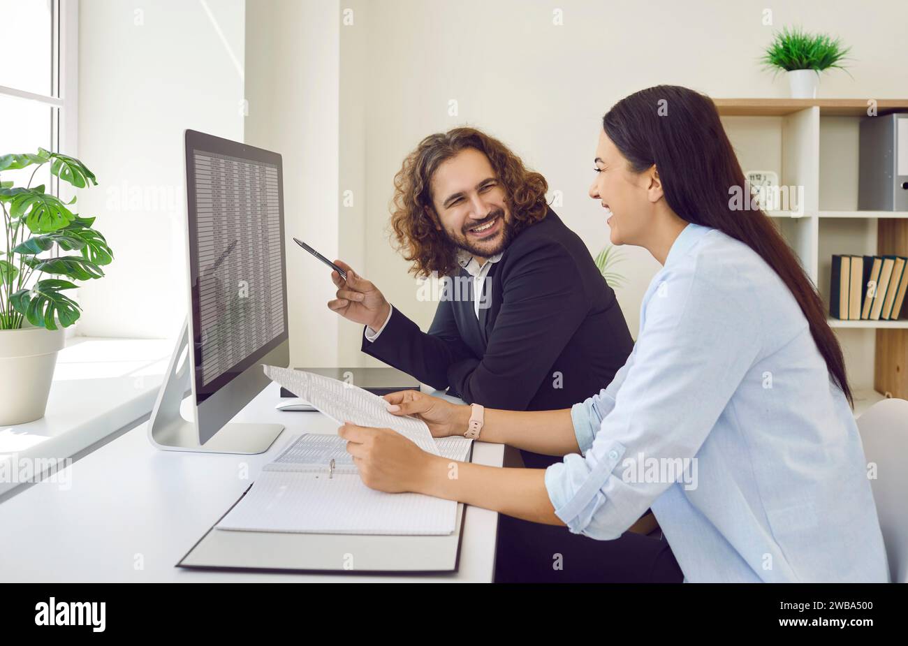 Two colleagues working with spreadsheets together, making funny jokes ...