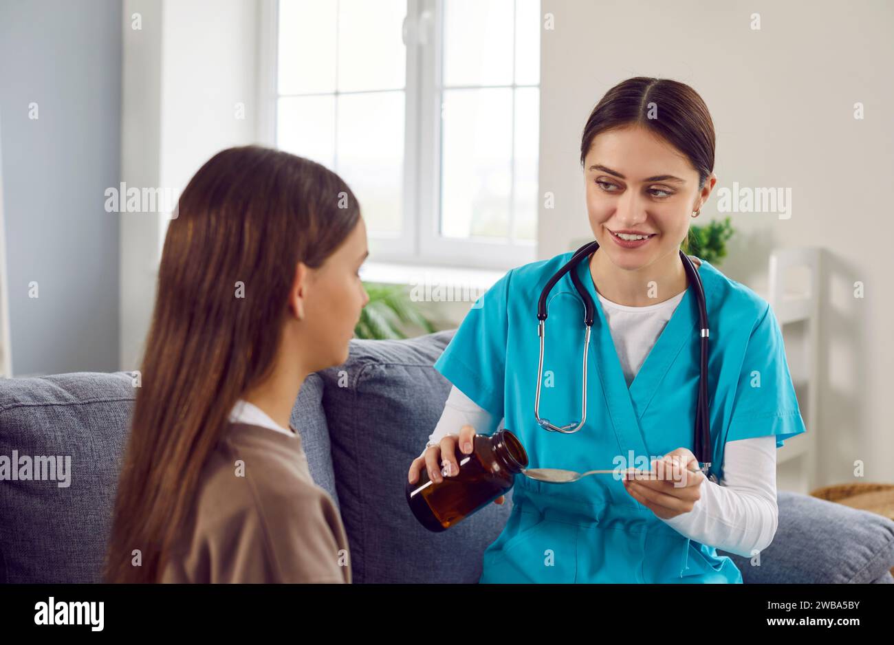 Young friendly nurse or pediatrician doctor giving cough syrup to a ...