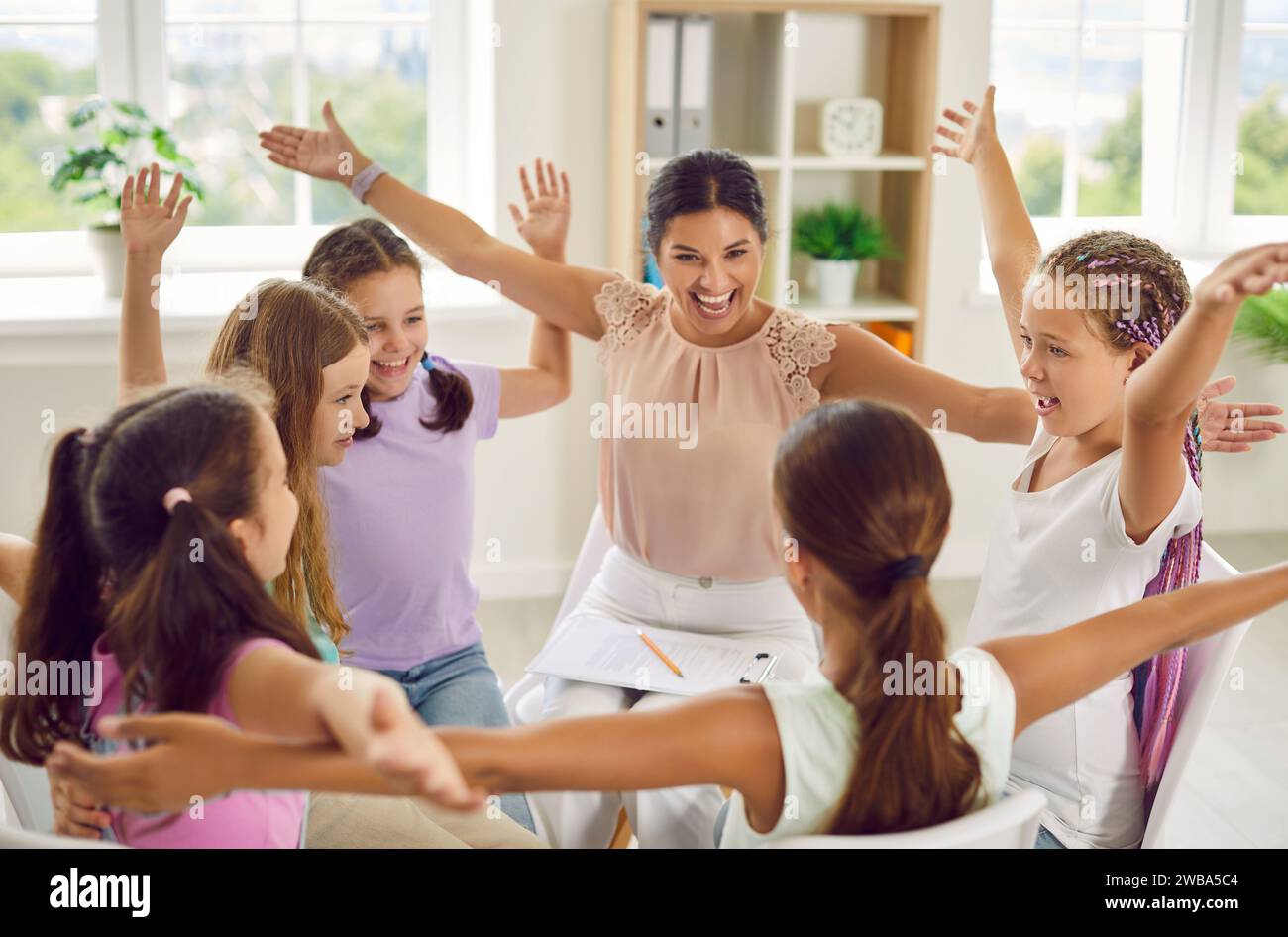 Group of school children girls sitting in a circle with psychologist ...